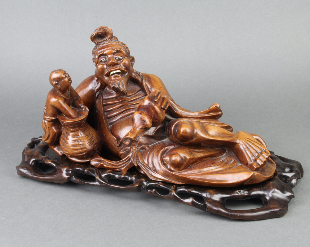 A carved Eastern figure of a reclining deity raised on | 19th October ...
